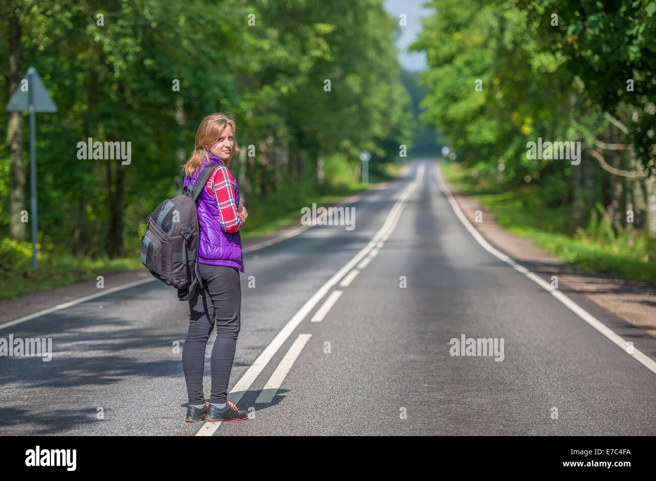 Beautiful girl with backpack walking on the road Stock Photo - Alamy