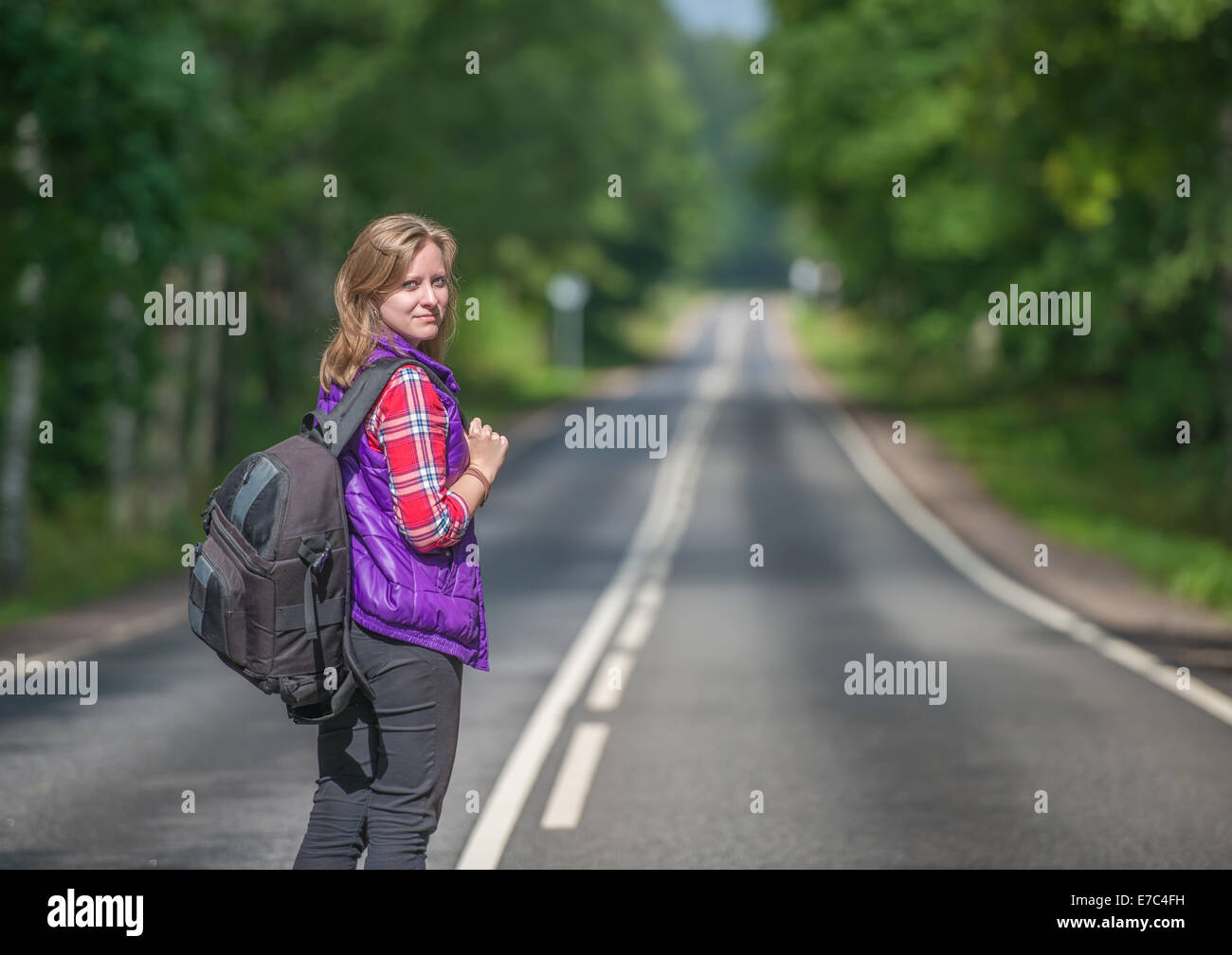 Beautiful girl with backpack walking on the road Stock Photo - Alamy