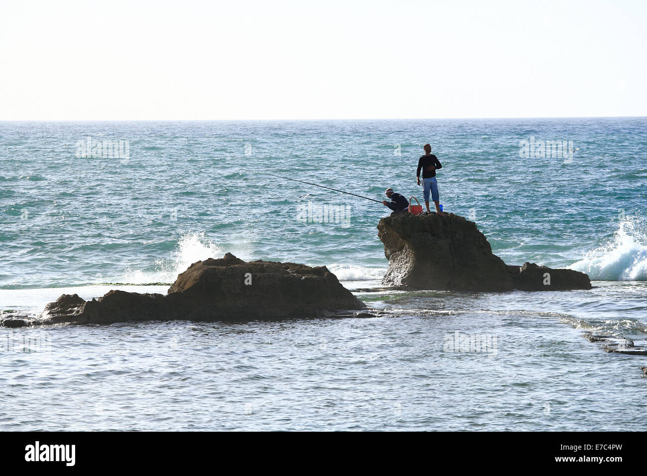 two fishermen fishing on rocks at coast of acre in northern israel at ...