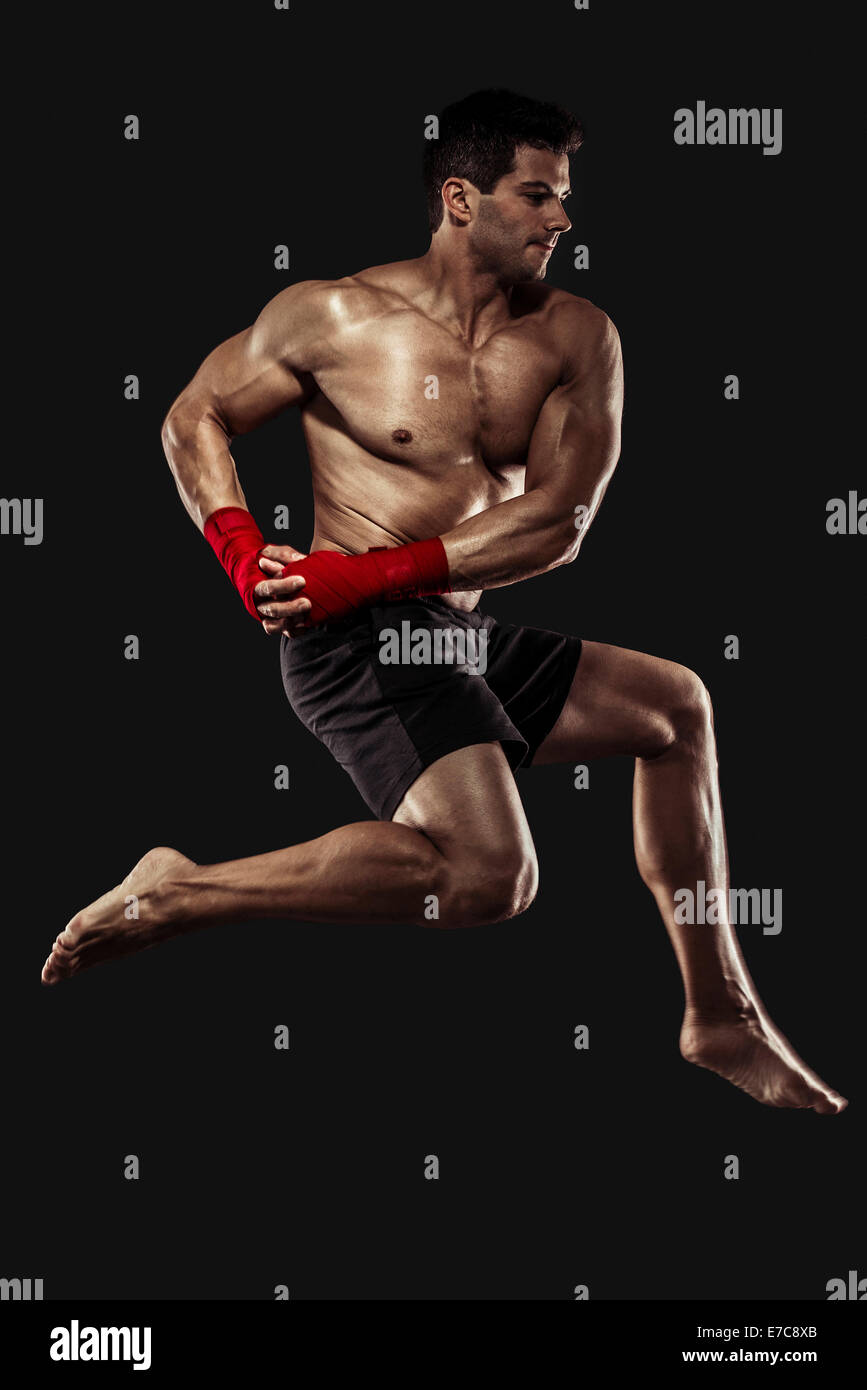 Portrait of a muscular man practicing body combat against a dark ...