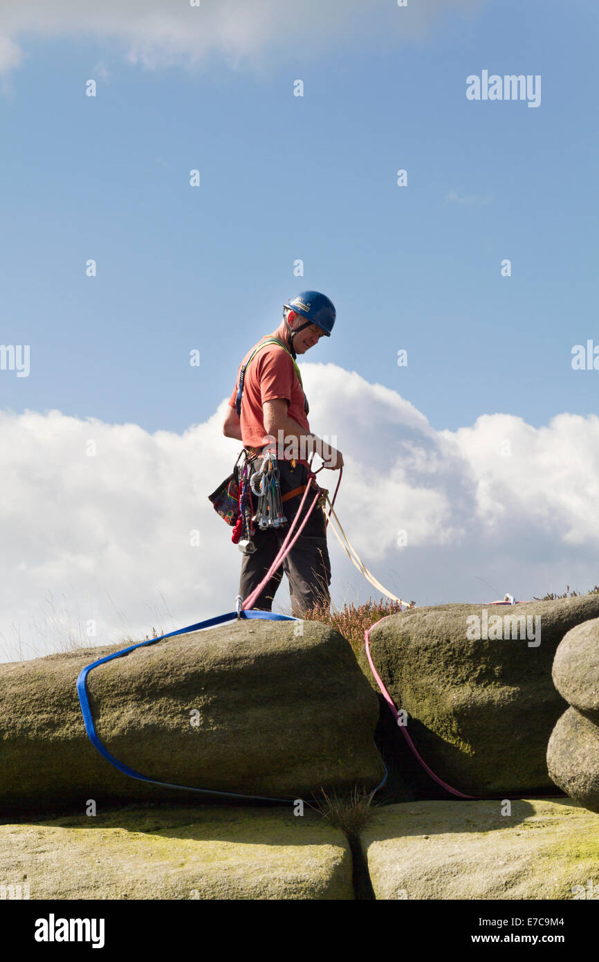 Rock climbing lead climber anchored to the top of the crag protecting ...