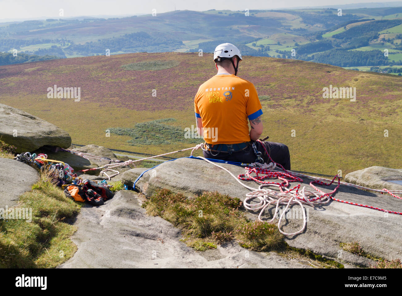 Rock climbing lead climber anchored to the top of the crag protecting ...