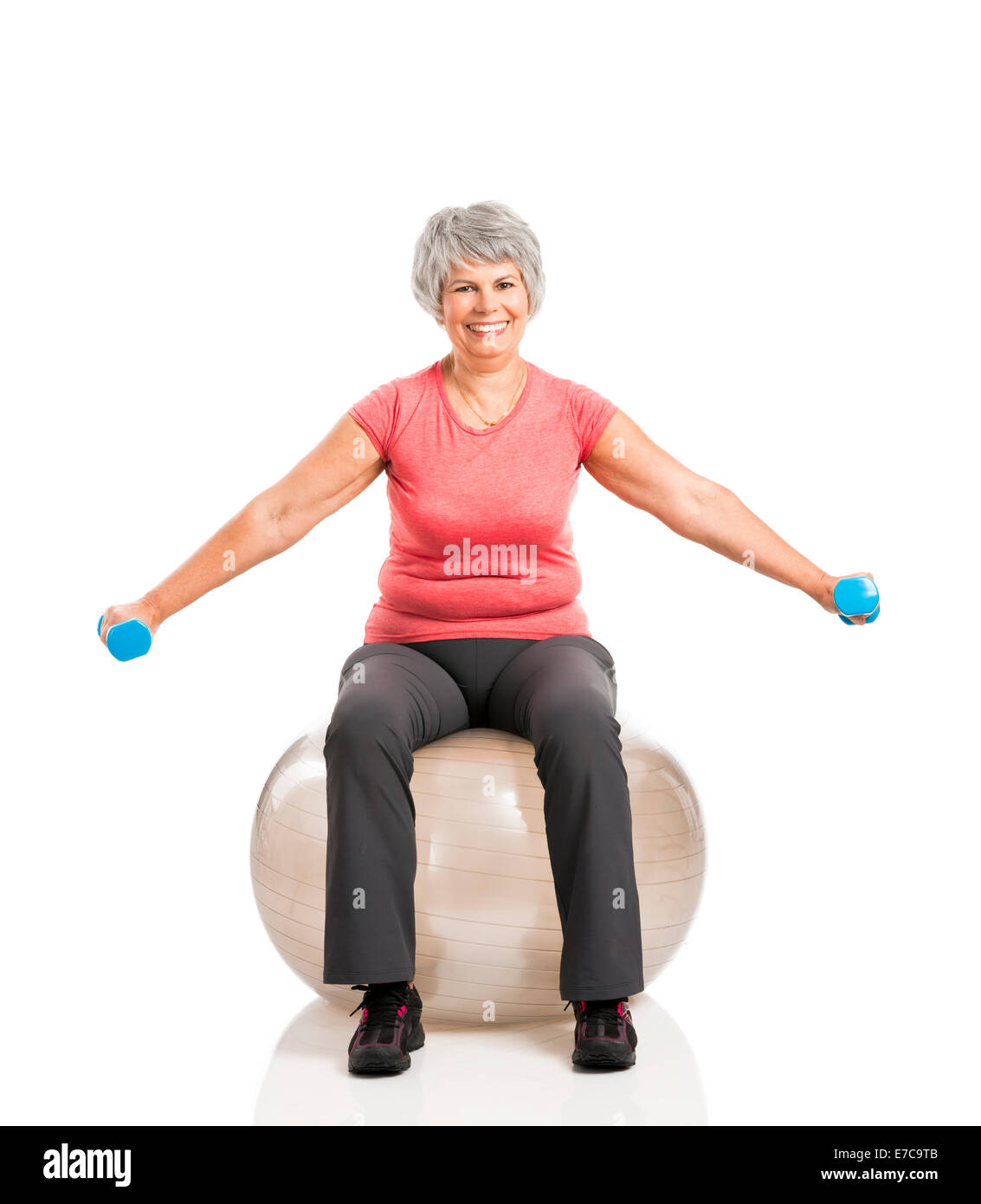 Happy fitness old woman lifting dumbbells while sitting over a PIlates ...