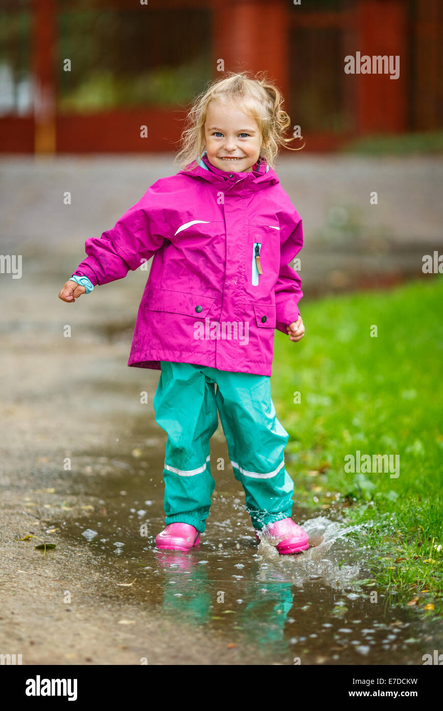 Happy little girl plays in a puddle Stock Photo - Alamy