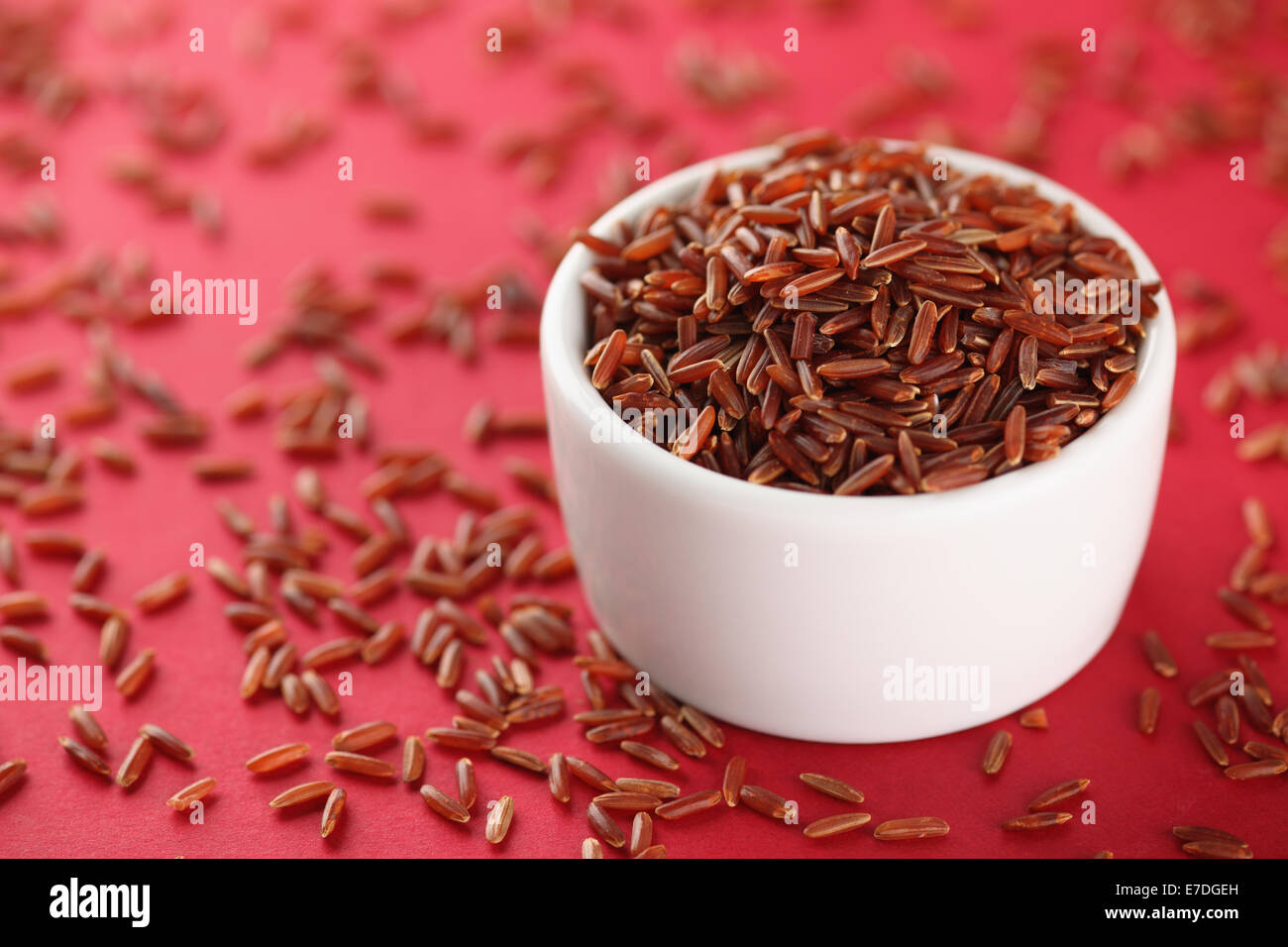 Red rice in a bowl. Red background Stock Photo - Alamy