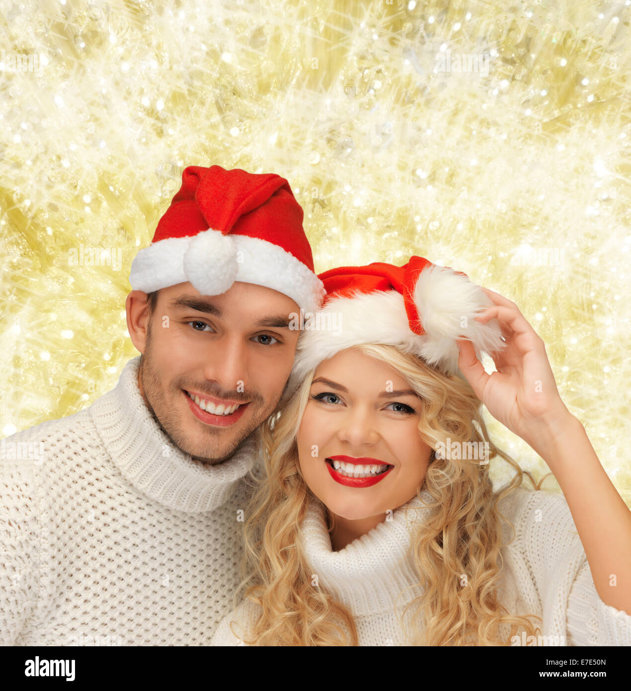 smiling couple in sweaters and santa helper hats Stock Photo - Alamy