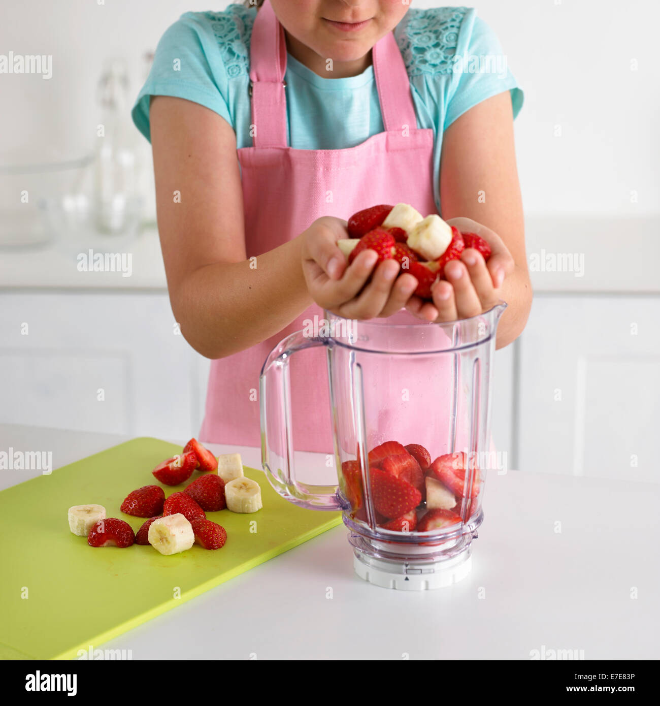 Girl placing strawberries and bananas into a blender, 8 years Stock ...