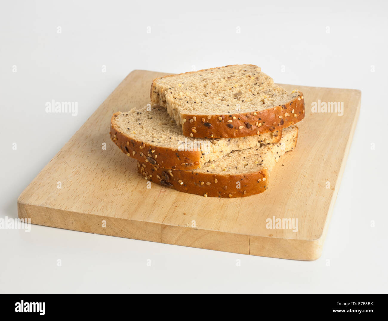 Three slices of seeded bread on breadboard Stock Photo - Alamy