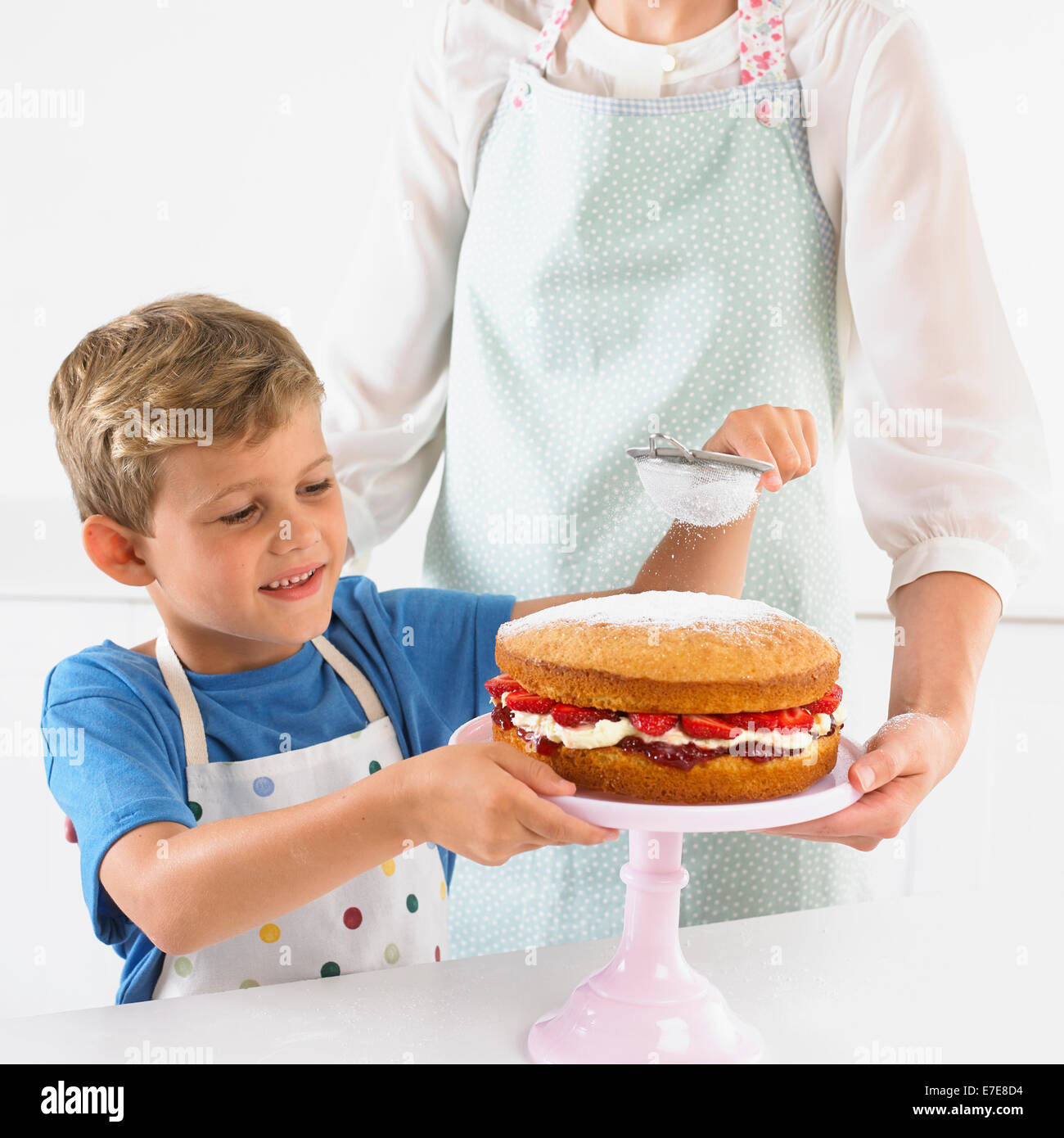 Boy sifting icing sugar over strawberry sponge cake Stock Photo - Alamy