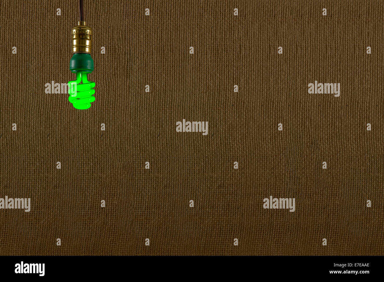 Single hanging green CFL (compact fluorescent lamp) in front of a ...