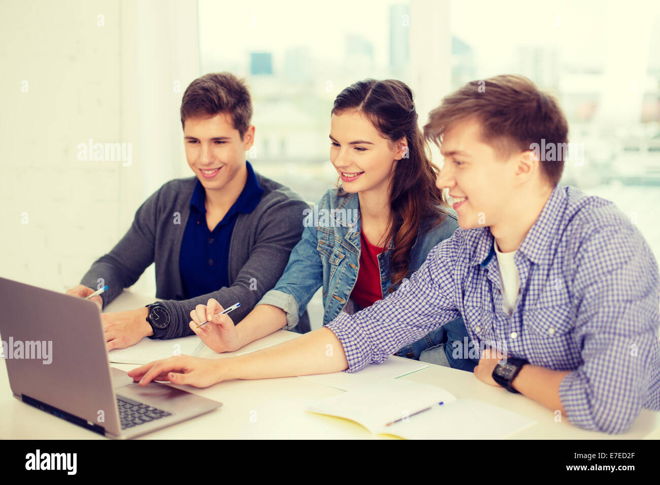 three smiling students with laptop and notebooks Stock Photo - Alamy