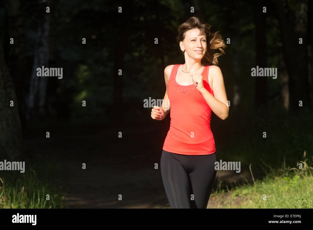 Cheerful girl jogging at morning in summer park. Smiling young ...