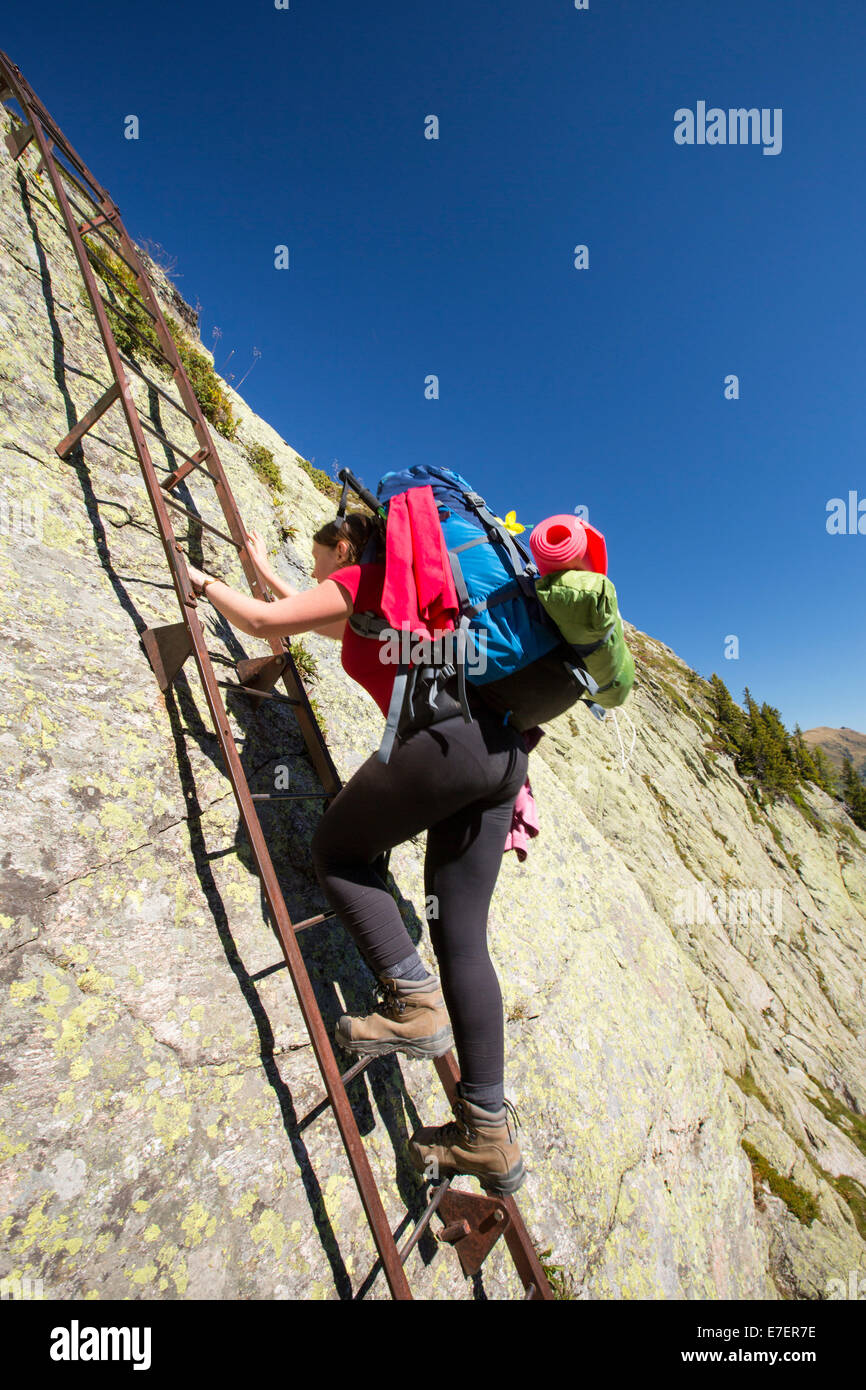 A woman climbing ladders in the Aiguille Rouge range above, Chamonix ...