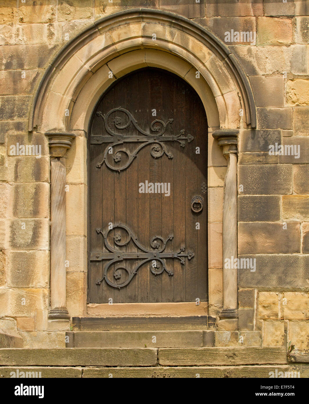 Dark brown wooden door with huge ornate iron hinges surrounded by ...