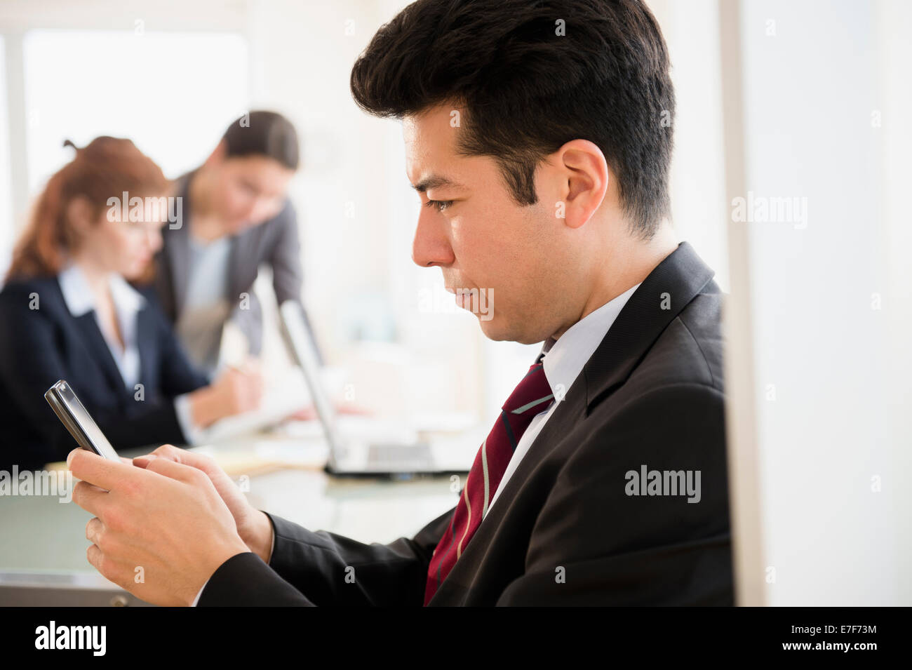 Businessman using cell phone in office Stock Photo - Alamy