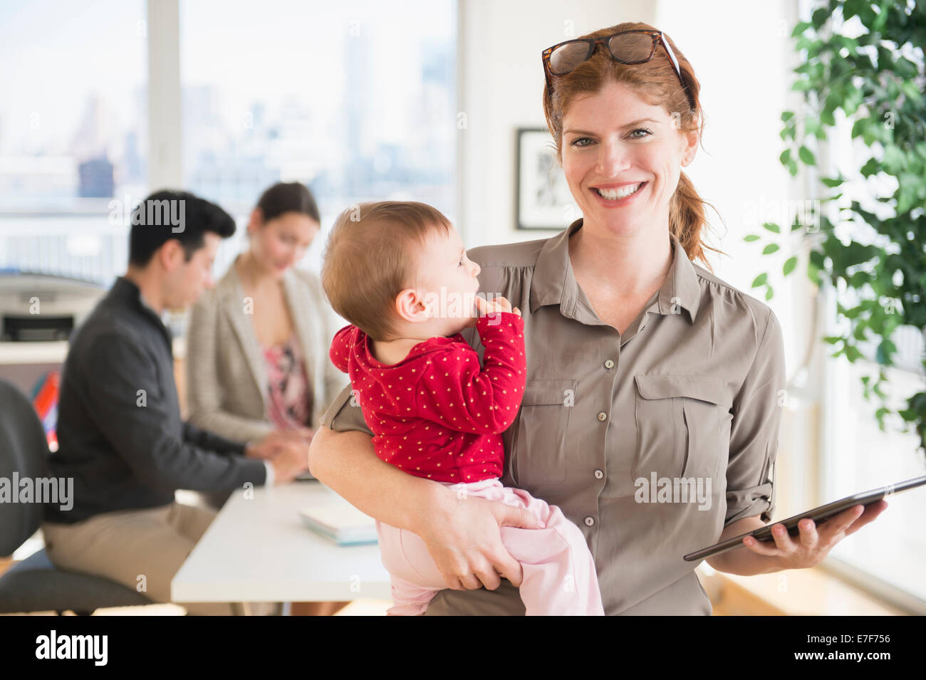 Businesswoman holding baby in office Stock Photo - Alamy