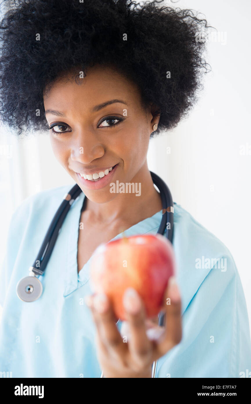 African American nurse holding apple Stock Photo - Alamy