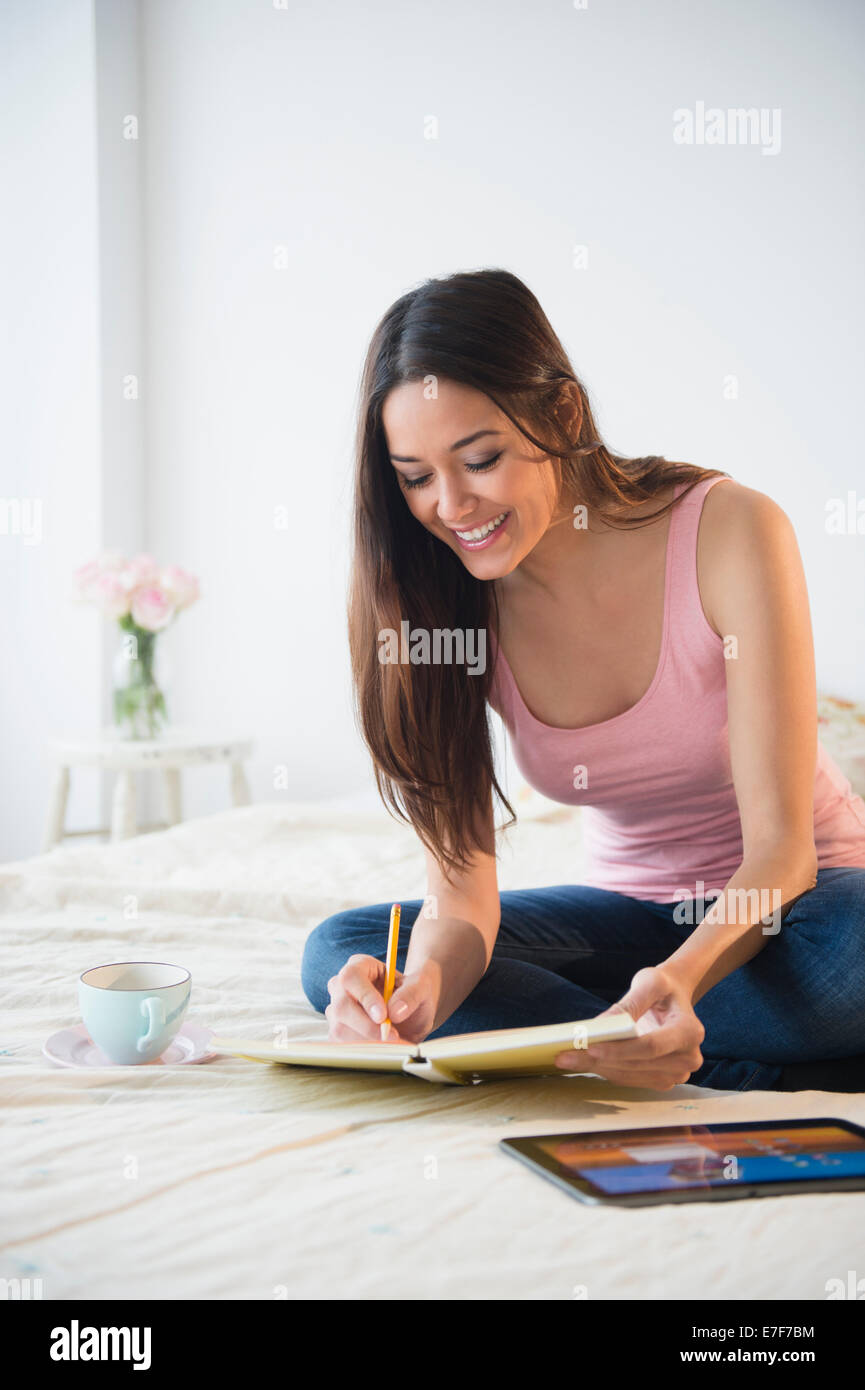 Woman taking notes with tablet computer on bed Stock Photo - Alamy