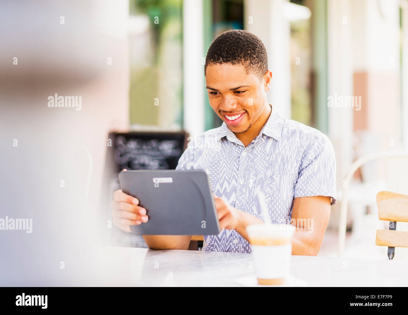 African American man using tablet computer at sidewalk cafe Stock Photo ...