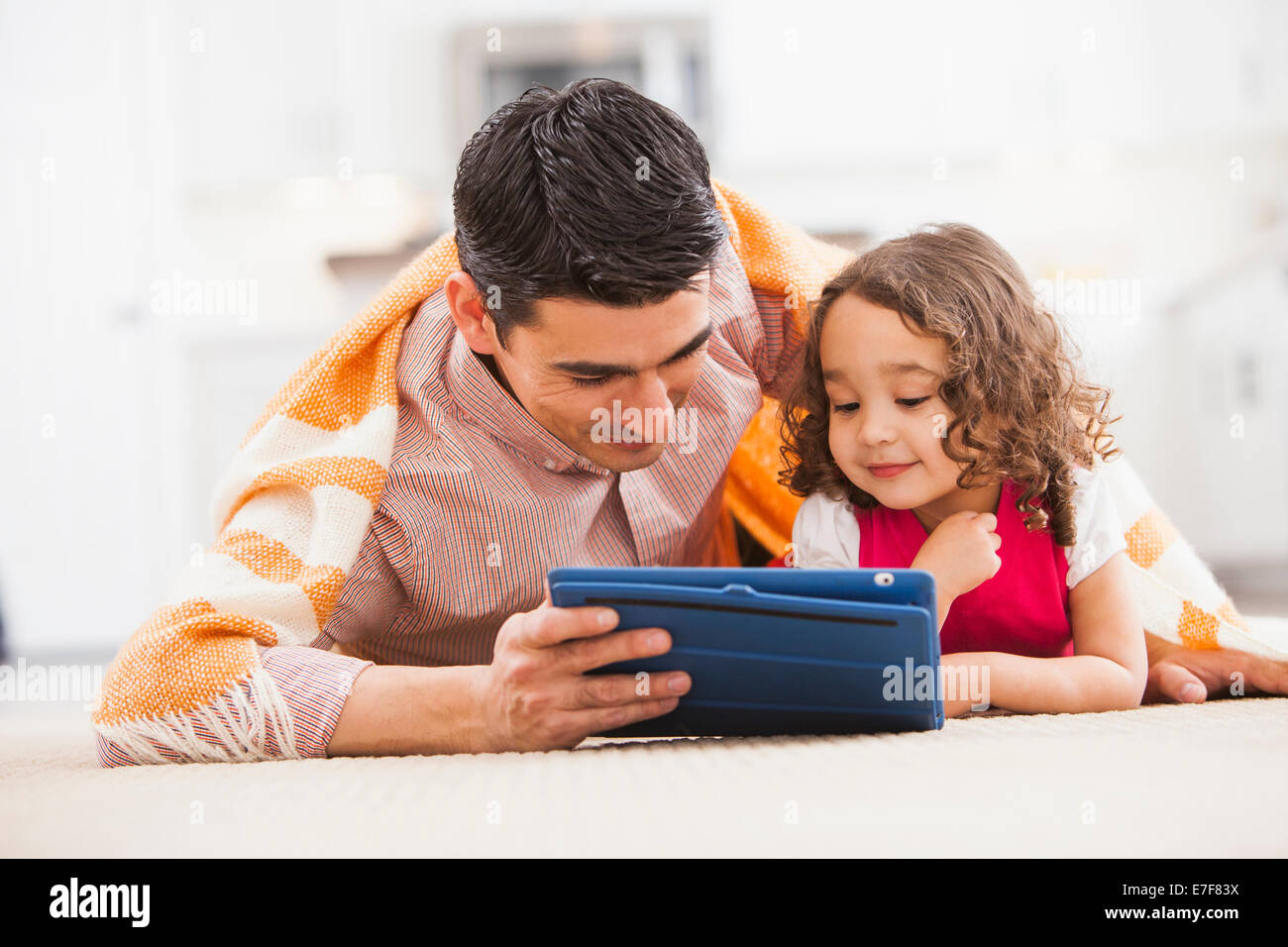 Father and daughter using tablet computer on living room floor Stock ...