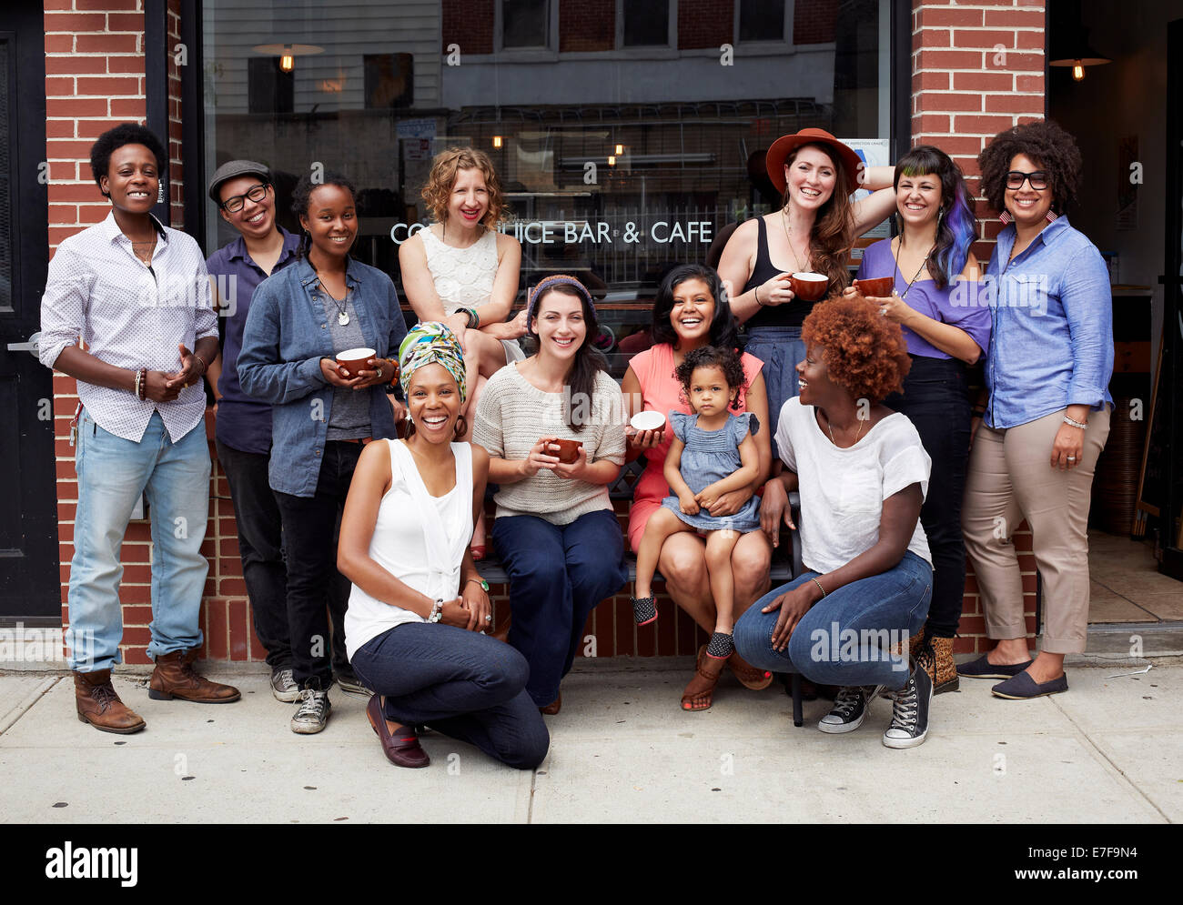 Friends sitting together outside coffee shop on city street Stock Photo ...