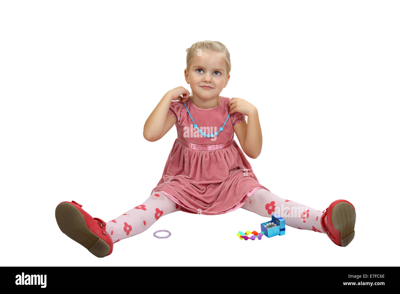 Cute little girl sits and try on jewelry. Portrait isolated on white ...