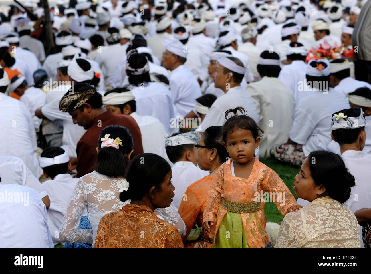 Small child with Mother, standing amidst seated crowd at religious ...