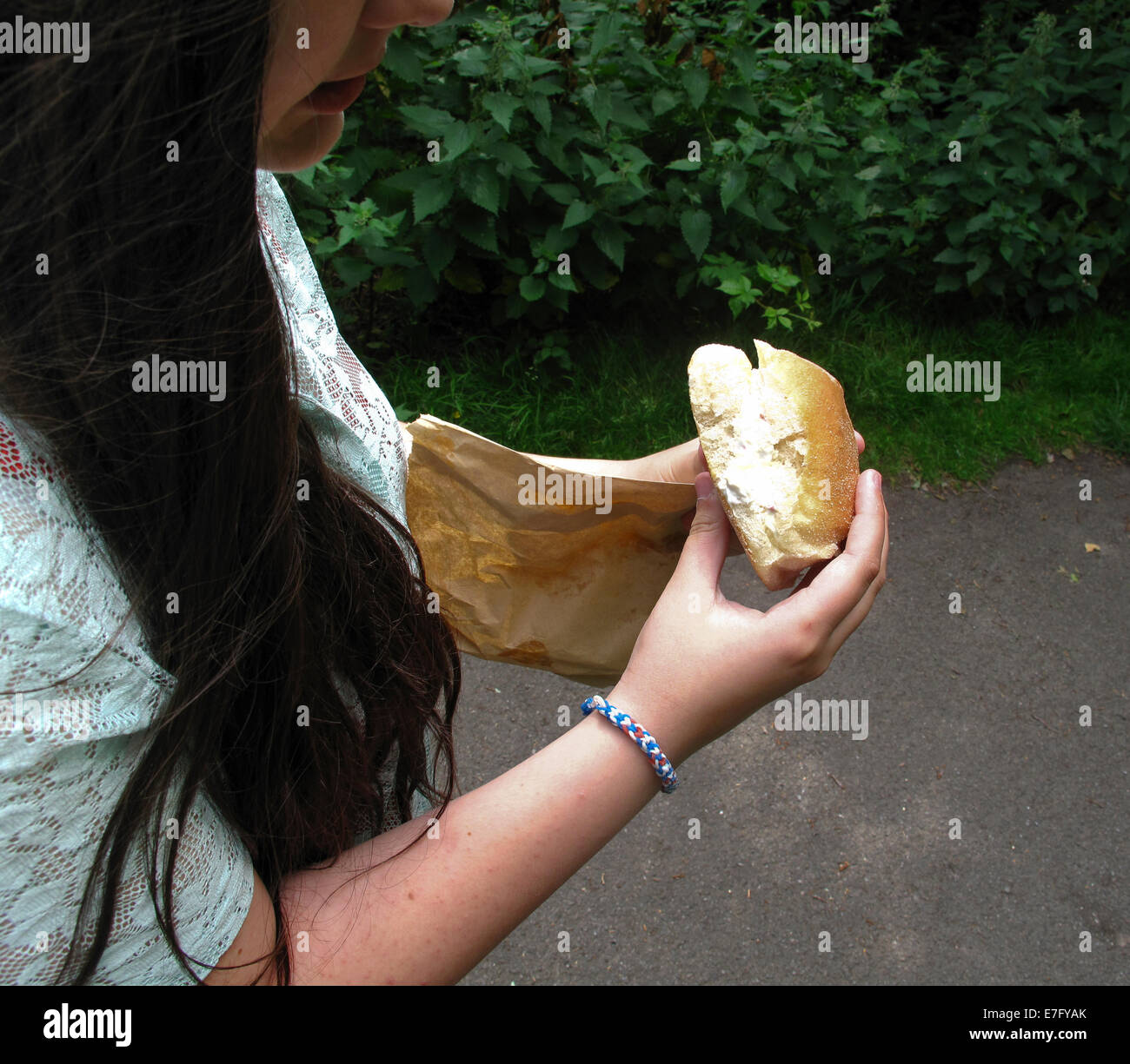 Young girl eating filled roll outside Stock Photo - Alamy