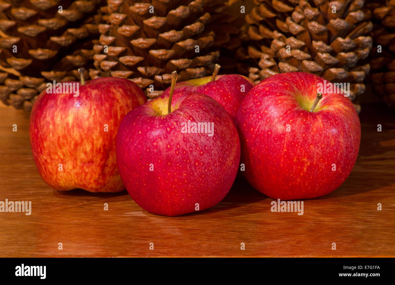 Red apples and pine cones on wooden table Stock Photo - Alamy