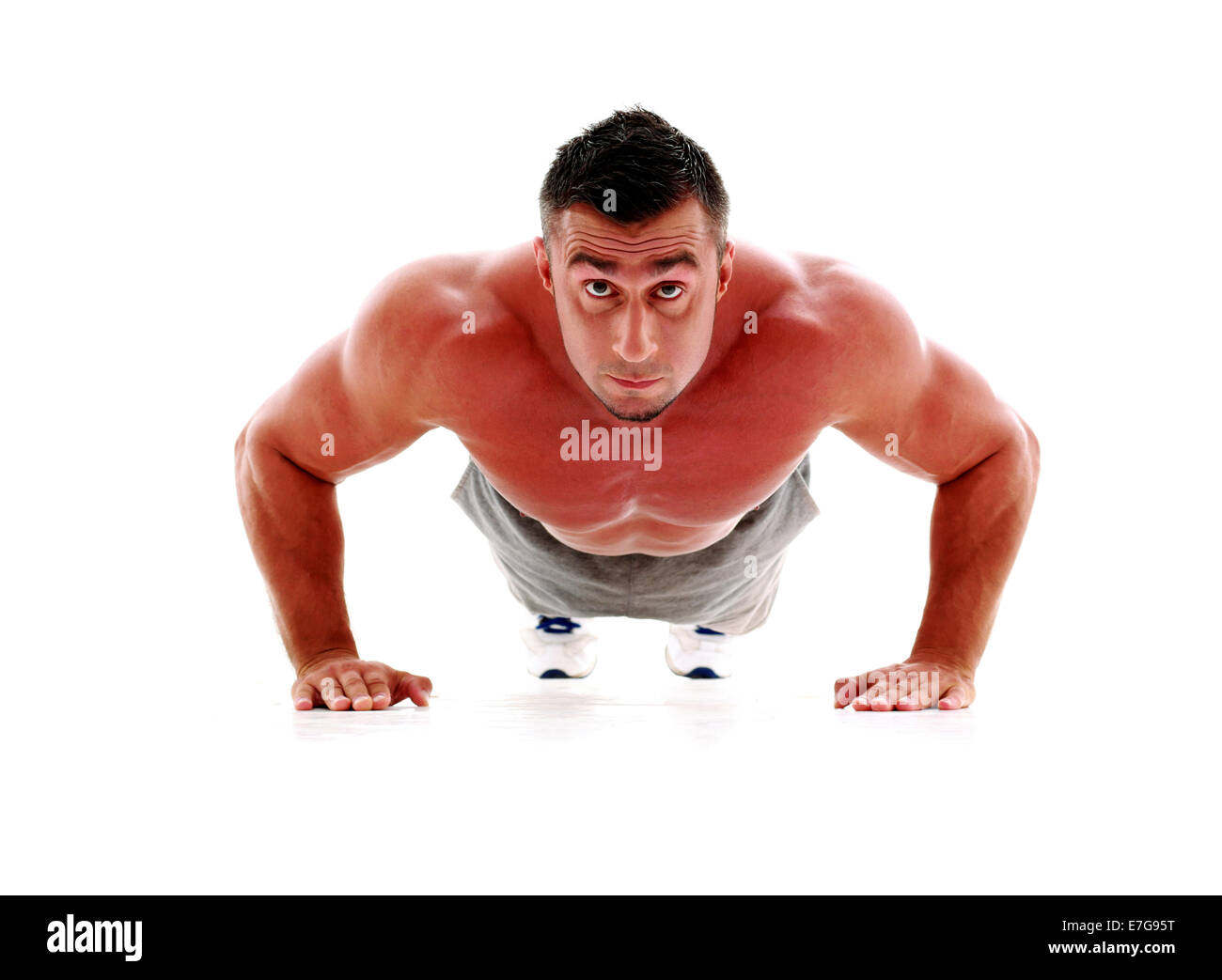 Muscle man making push ups in studio, isolated over a white background ...