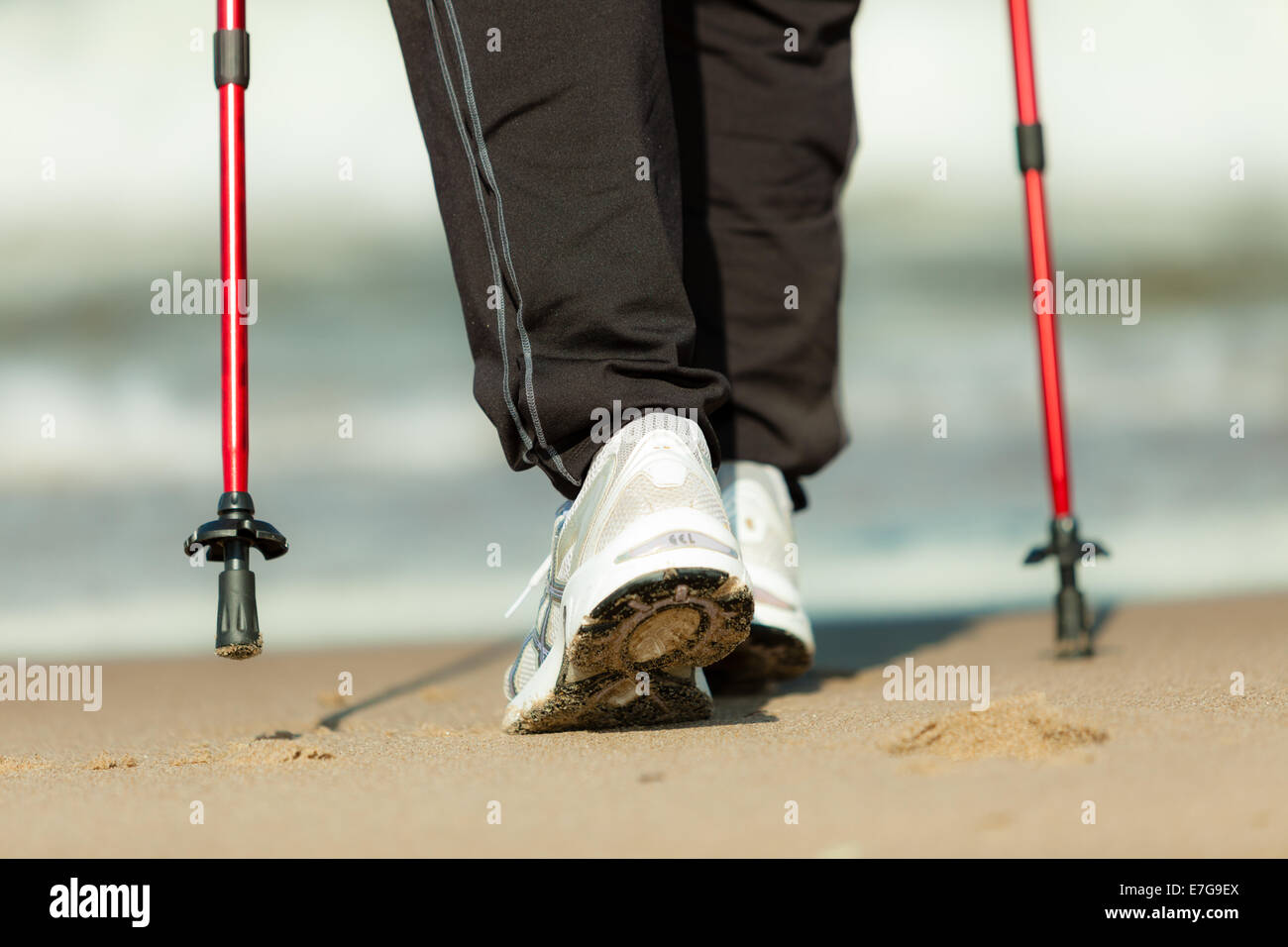 Nordic walking. Closeup of female legs hiking on the beach. Active and ...