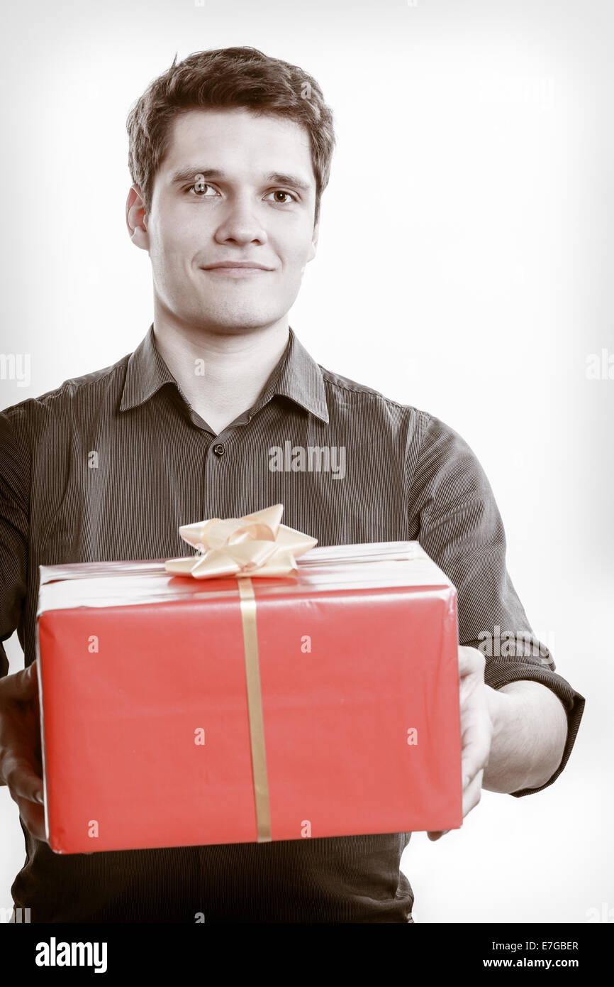 Holiday and special occasion. Young handsome man giving red present ...