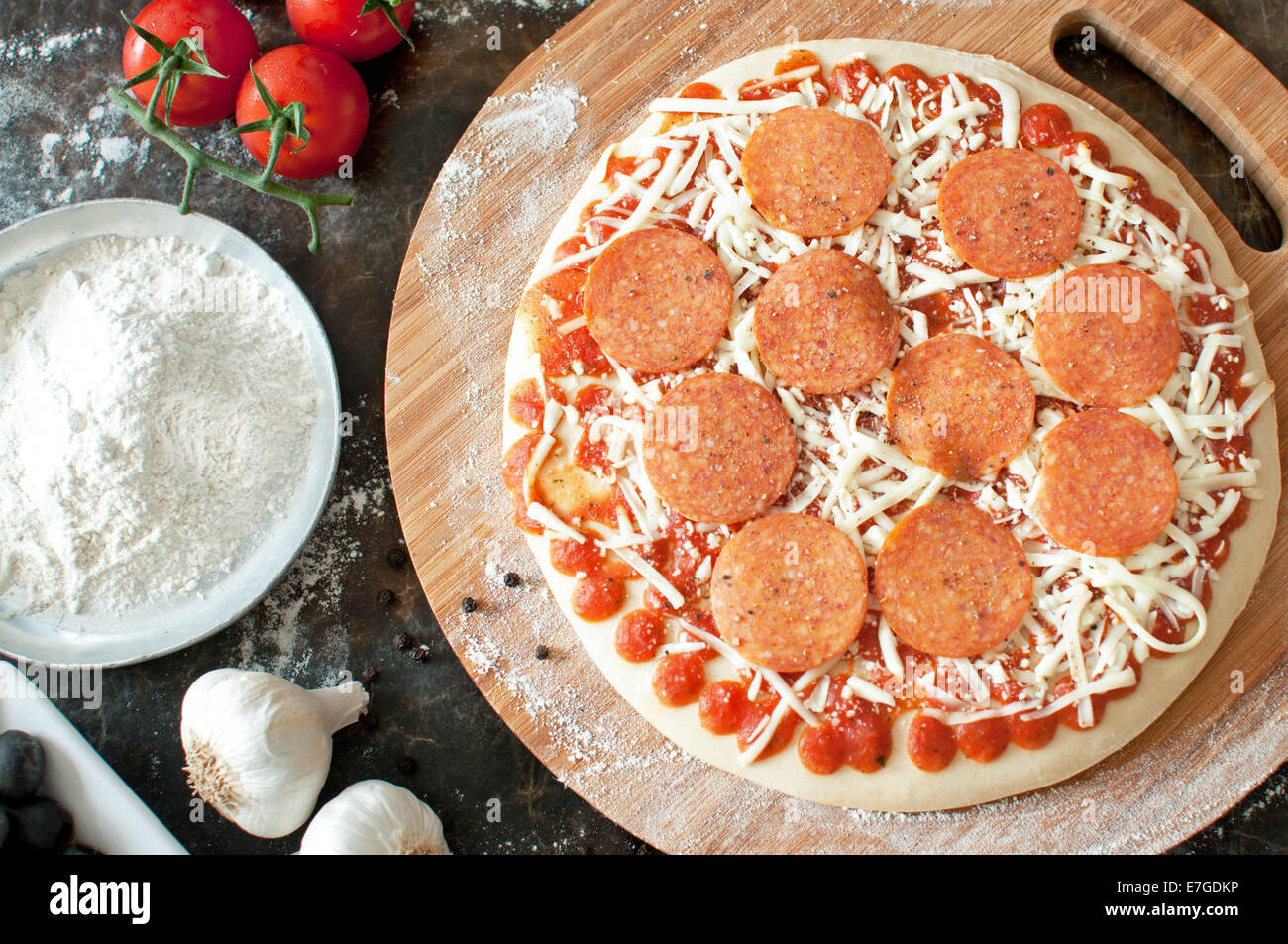 Pepperoni pizza preparation with fresh ingredients on a kitchen table ...