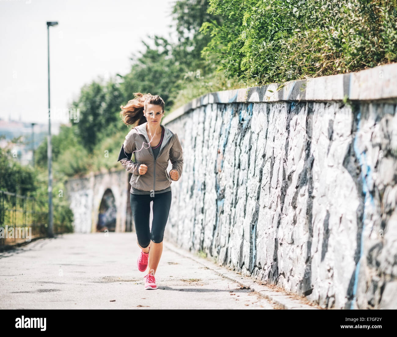 Full length portrait of fitness young woman jogging in the city park ...