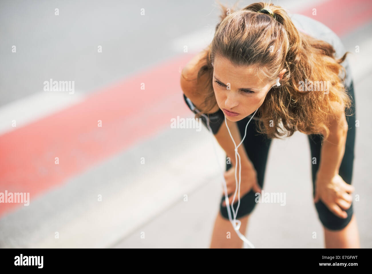 Portrait of tired fitness young woman outdoors in the city catching ...