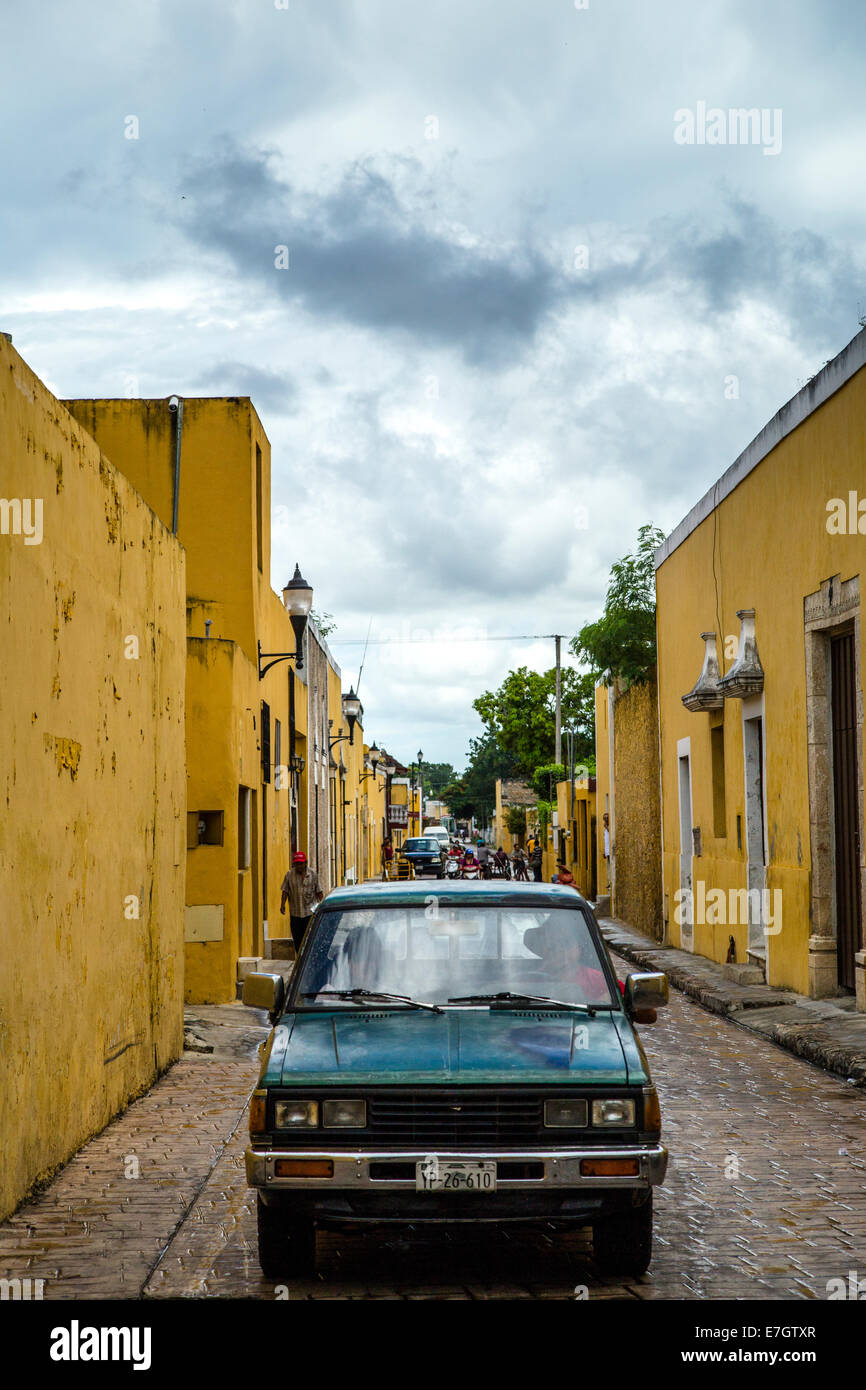 old colonial street with yellow houses and an old truck in a small town ...