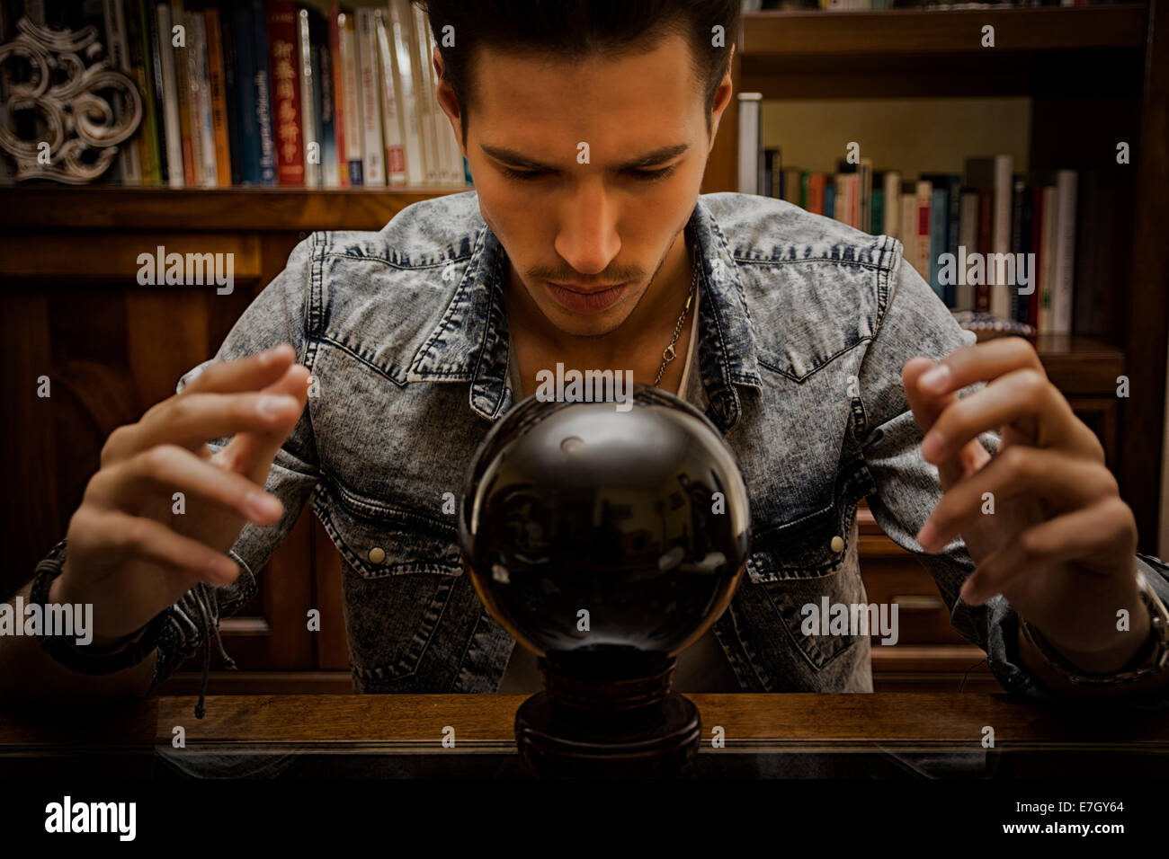 Handsome young man predicting the future by looking into black crystal ...