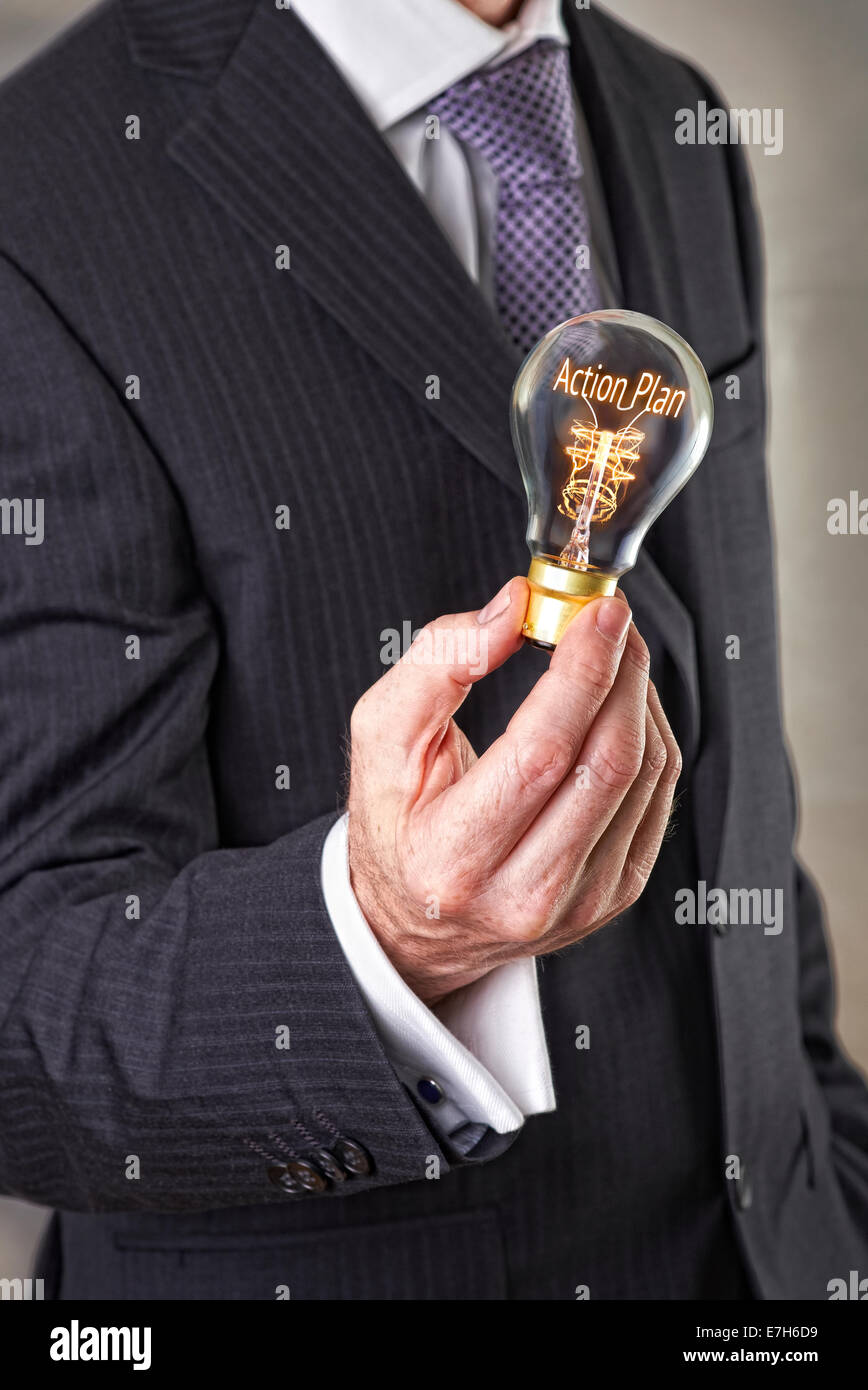 Businessman holding a lit lightbulb concept with the word Action Plan ...