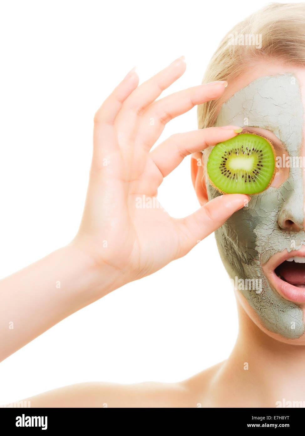 Skin care. Surprised woman in clay mud mask with kiwi fruit on face ...