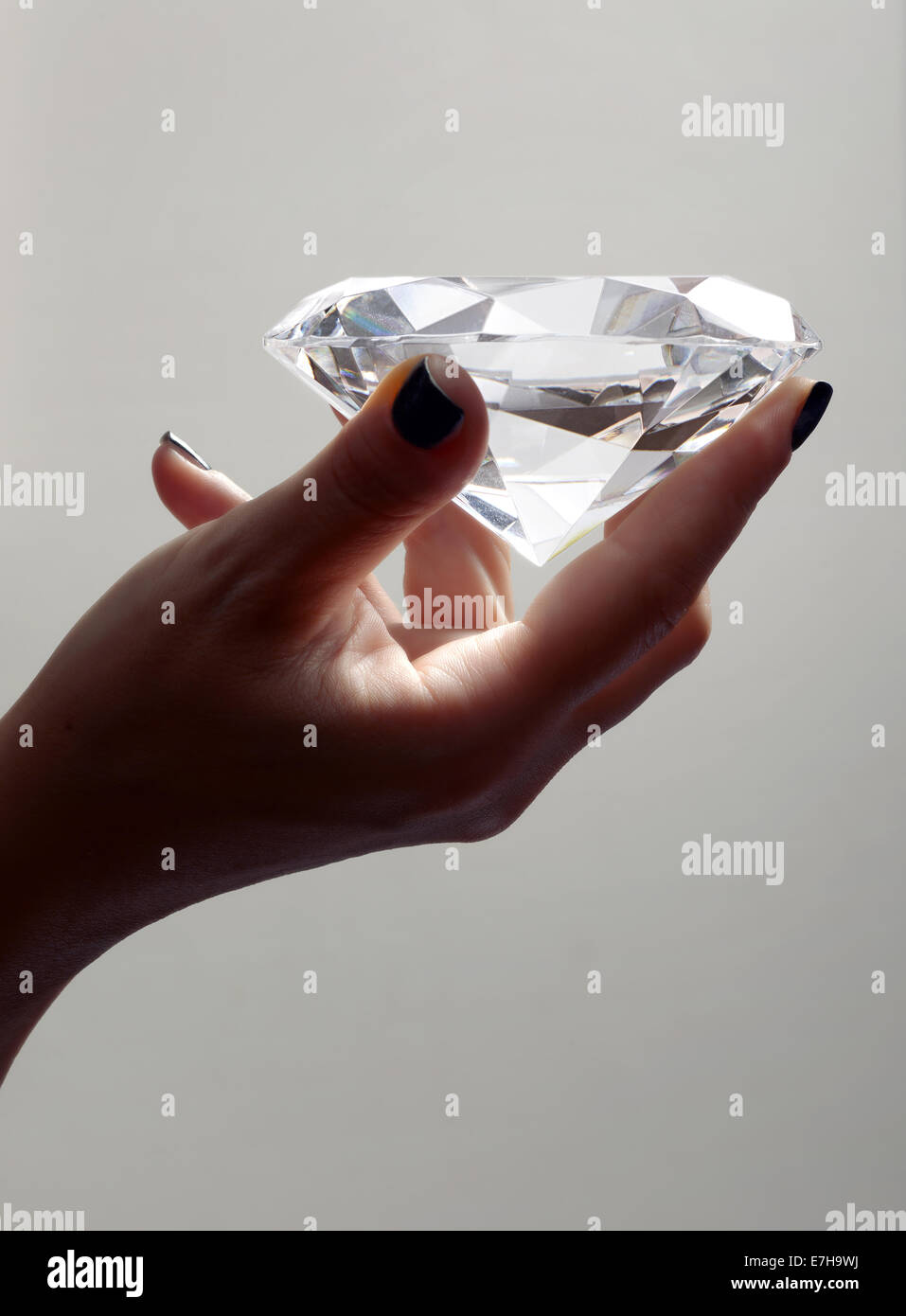 Female Hand Holding Over sized Illuminated Diamond in Studio with Grey ...