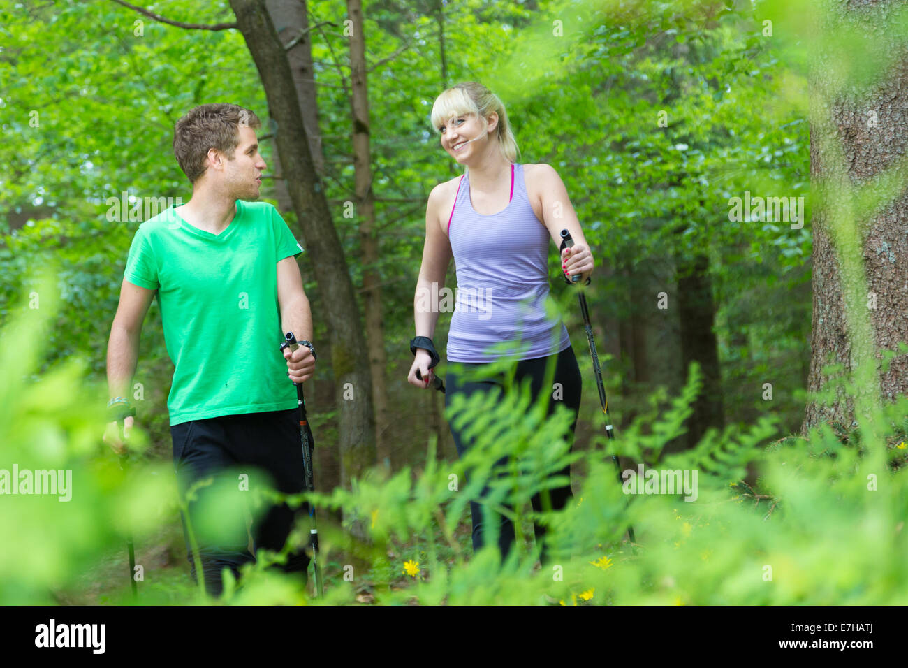 Young sporty active couple with hiking sticks walking in nature. Active ...