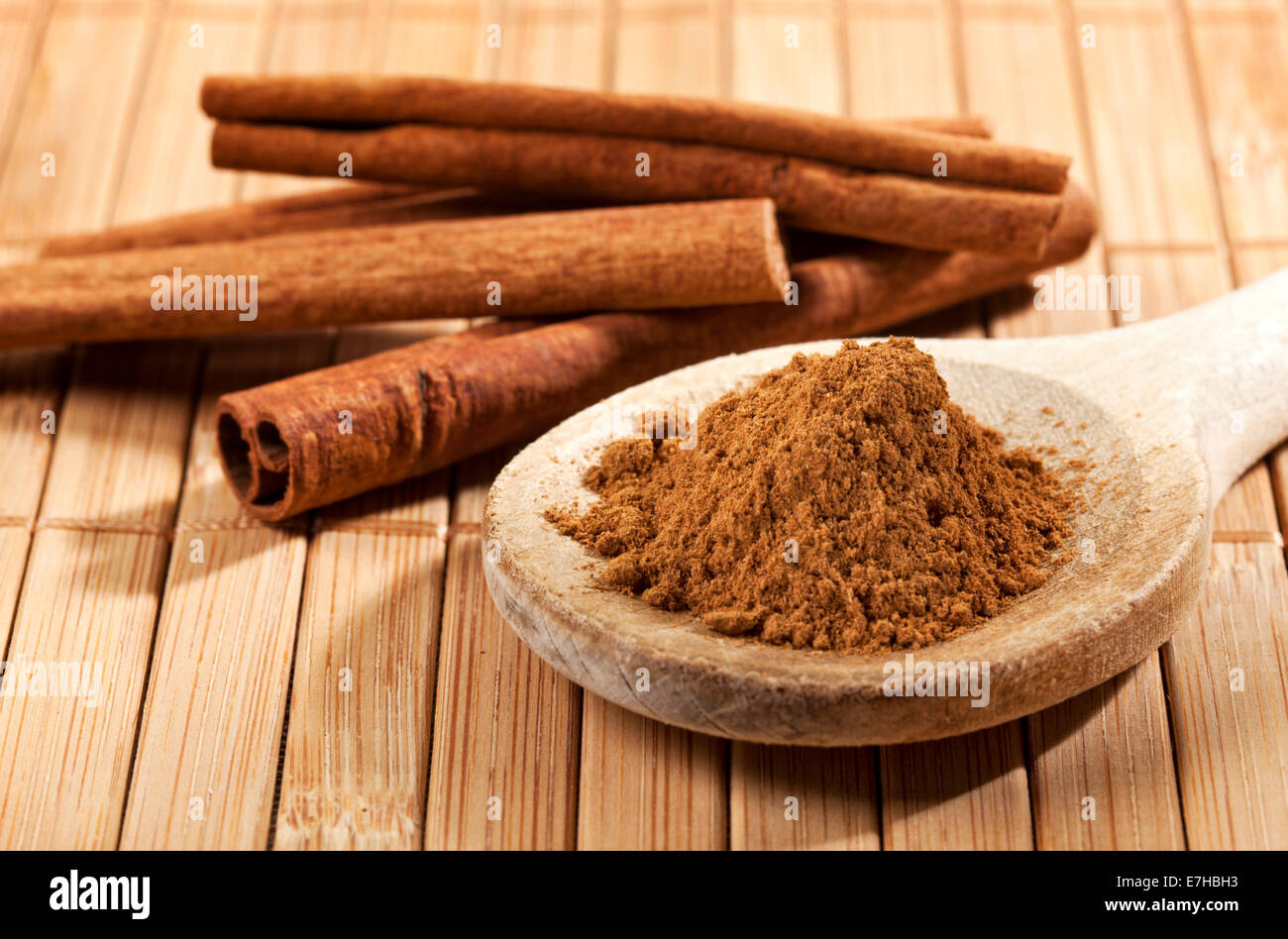 Ground cinnamon on wooden spoon, cinnamon sticks in background Stock ...