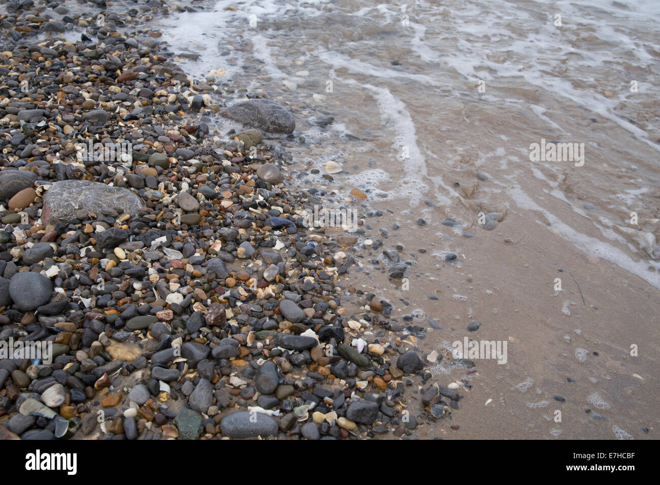 Pebble beach background with sea coming in Stock Photo - Alamy