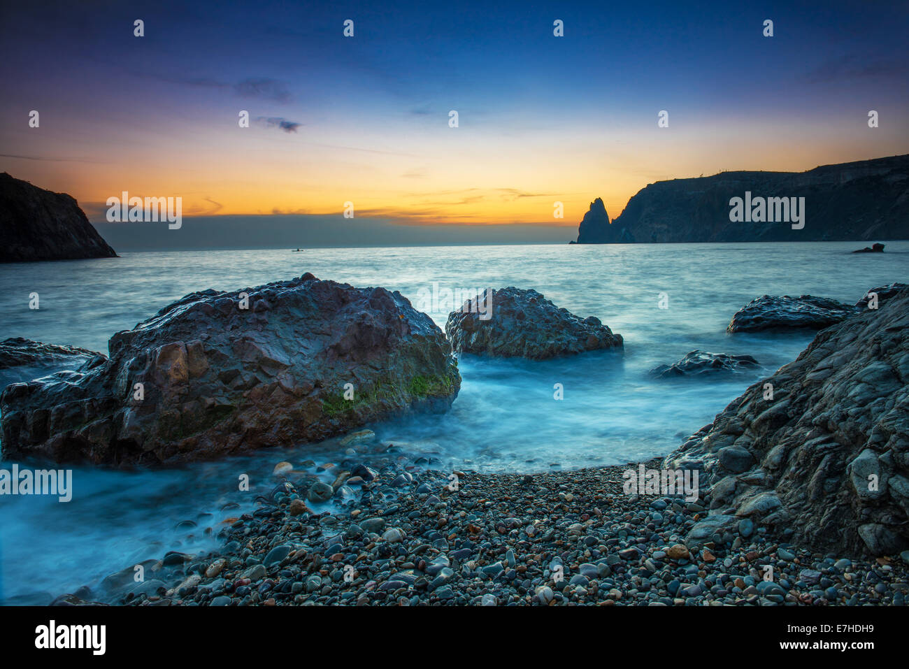 Sunset on the beach with sea, rocks and dramatic sky Stock Photo - Alamy