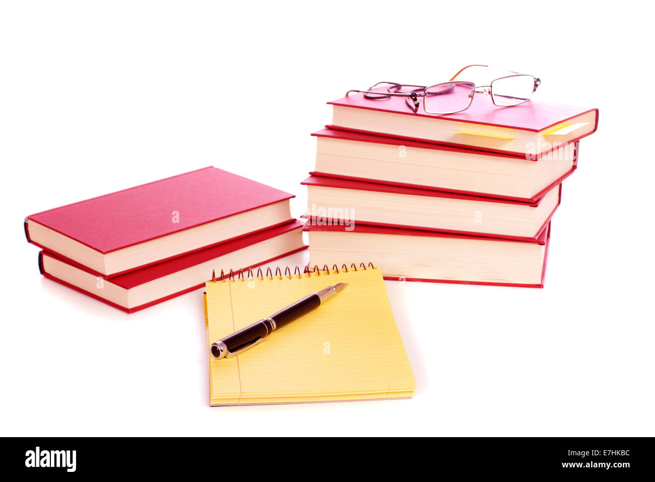One pen on notebook, some books and reading glasses isolated over white ...