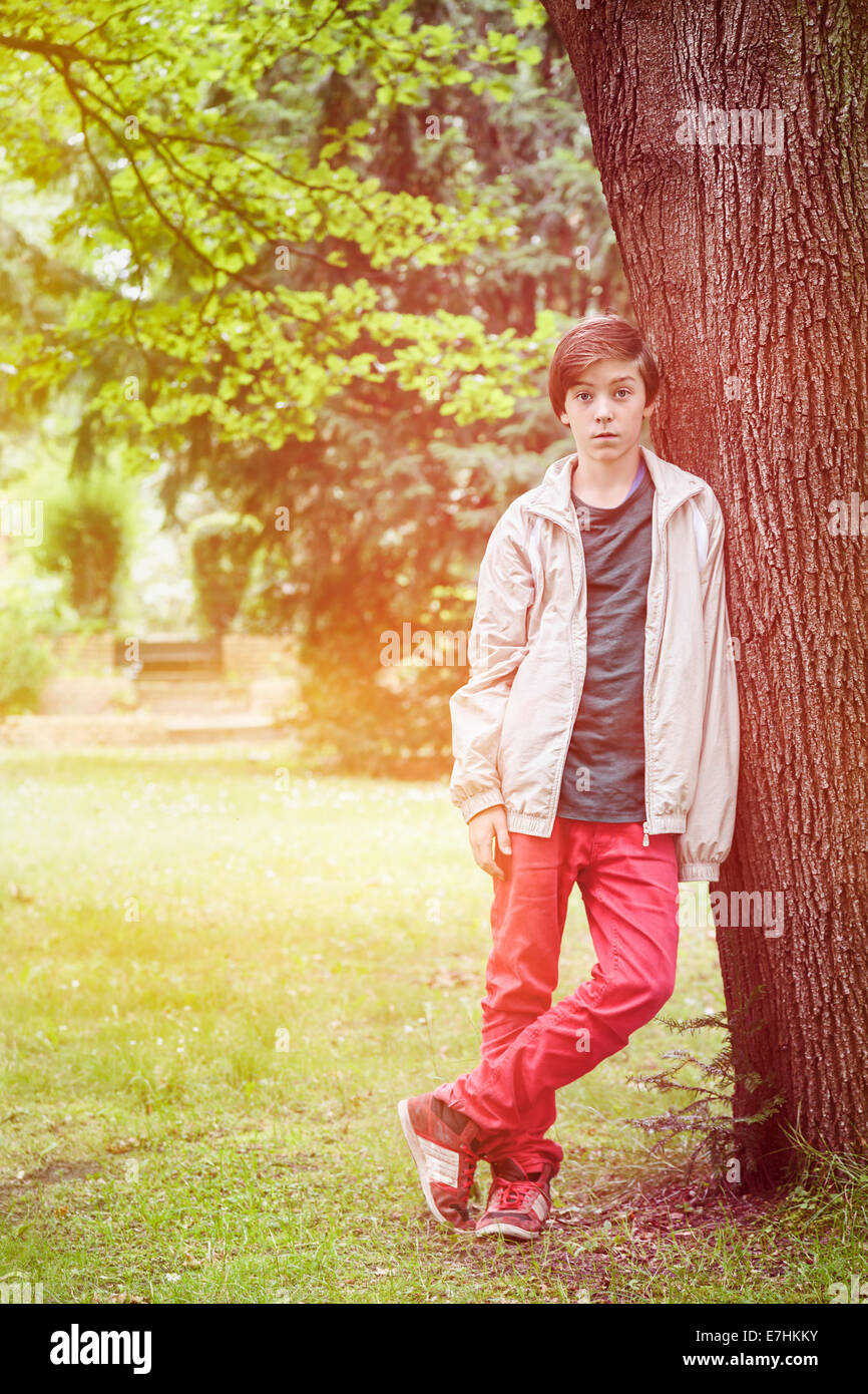 Boy leaning against tree in hi-res stock photography and images - Alamy
