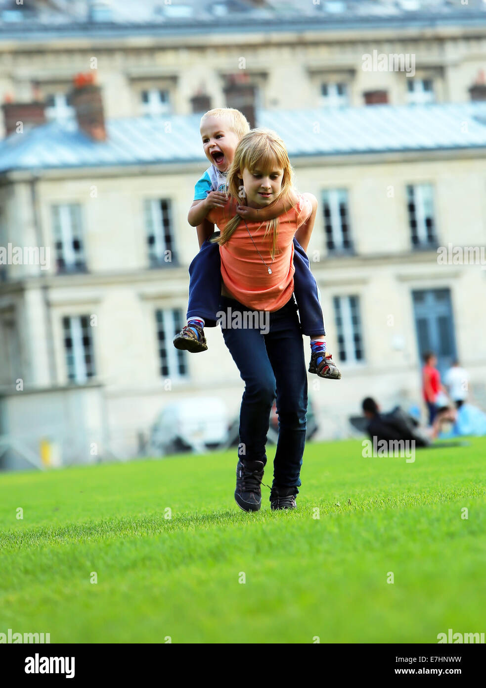 Happy kids, school girl and her little brother, playing in city park ...