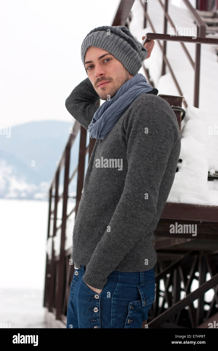Young man in winter holding on to some iron bars Stock Photo - Alamy