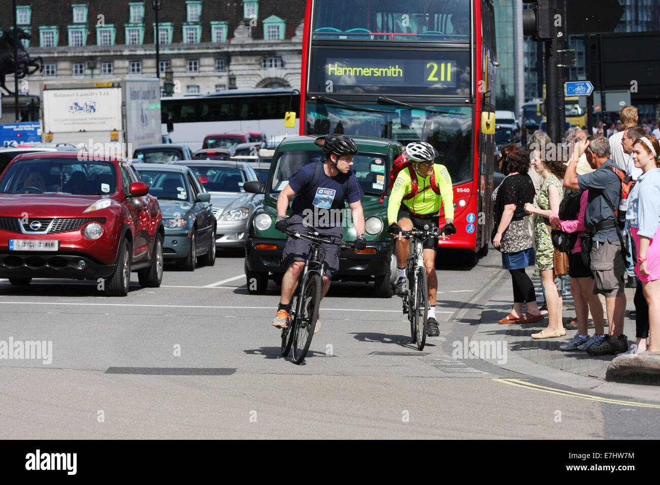 Two cyclists move off from a set of traffic lights in front of a queue ...
