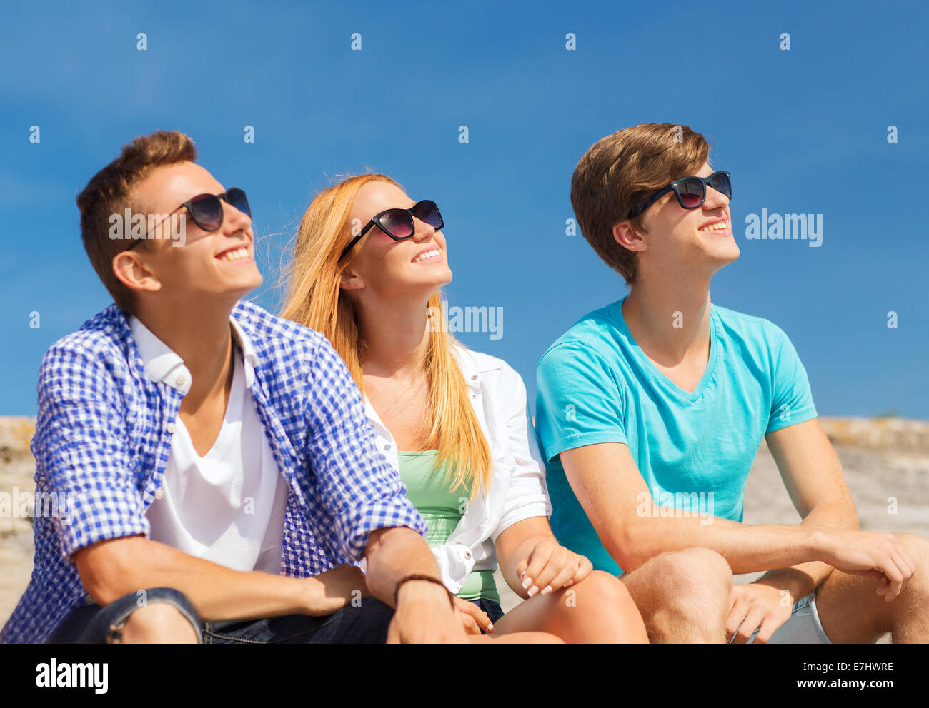 group of smiling friends sitting on city street Stock Photo - Alamy